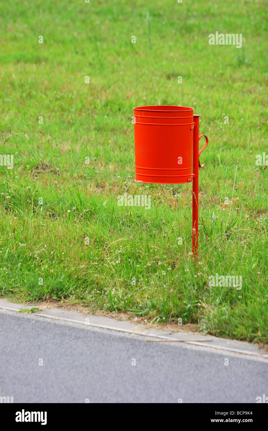 red garbage can on the grass by the road Stock Photo - Alamy