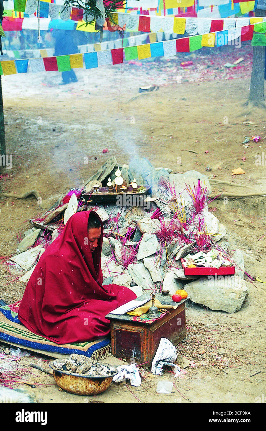 Lama sitting meditating beside incense ash pile on the roadside ...