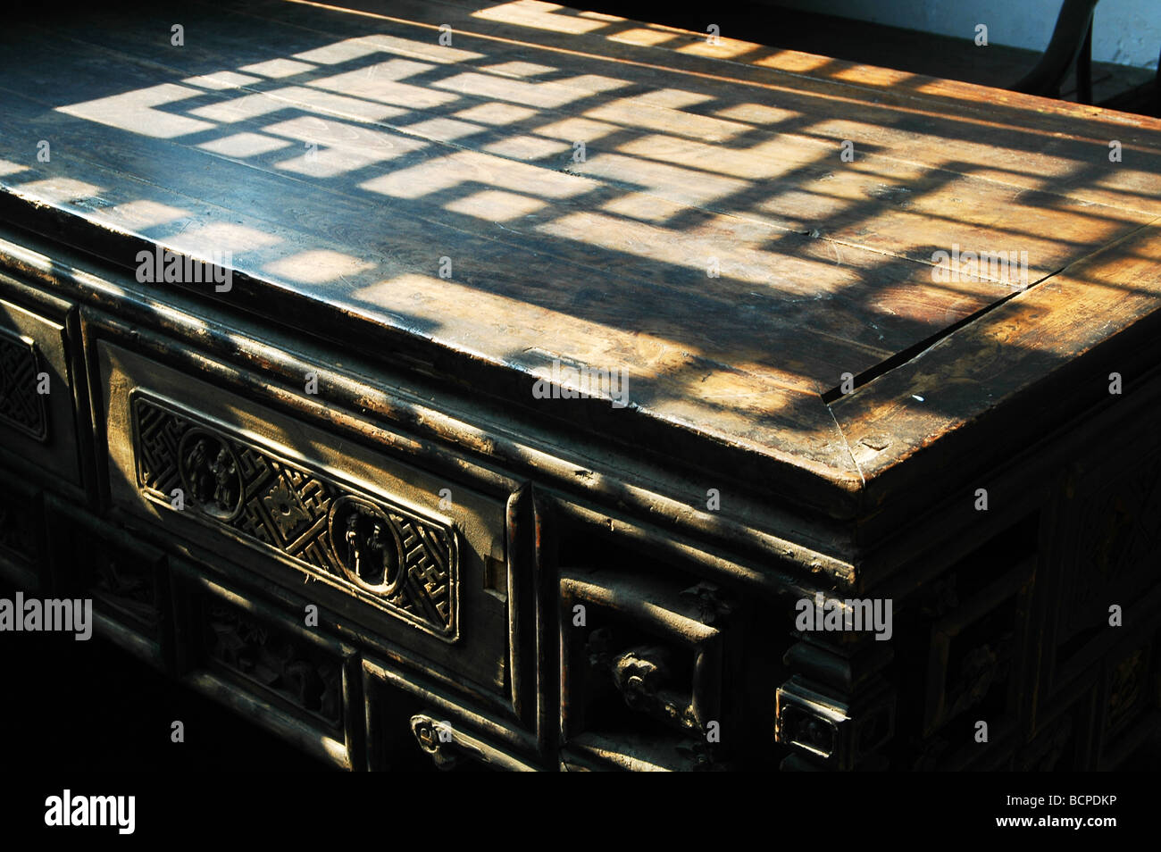Sunlight stroking the aged surface of an ancient desk, casting shadow ...