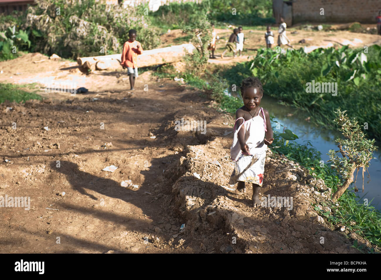 Young girl walking along side of drainage ditch in Kampala slum Stock ...