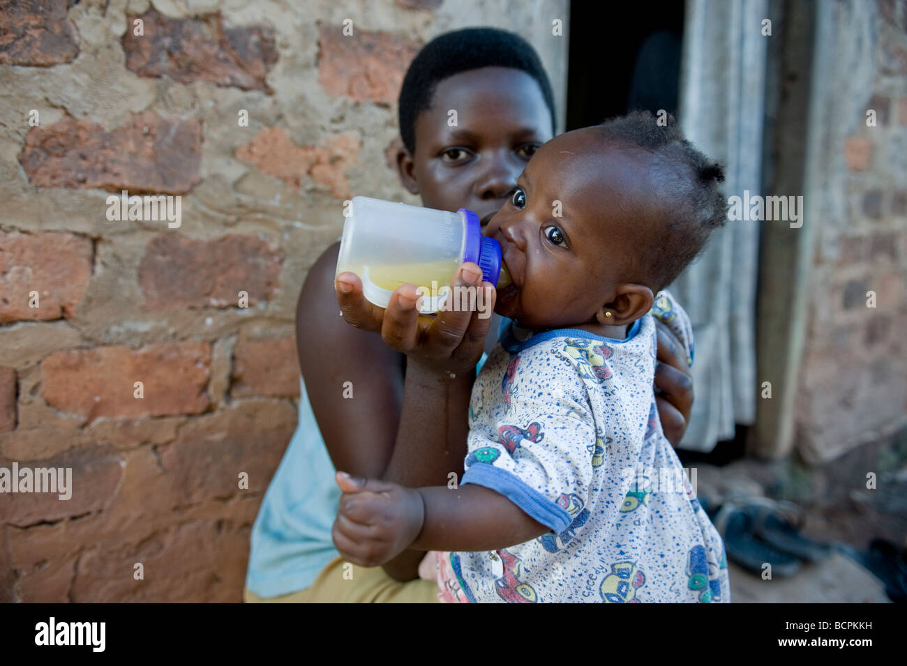 Baby girl feeding from bottle in ugandan slum Stock Photo - Alamy