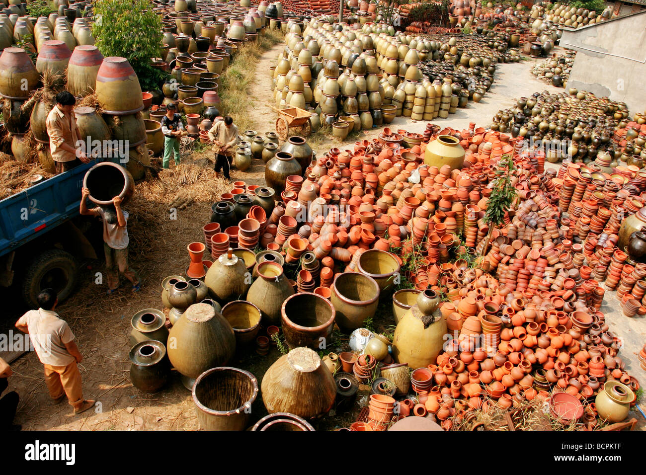 Labors moving clay pots made using century old technique onto a truck ...