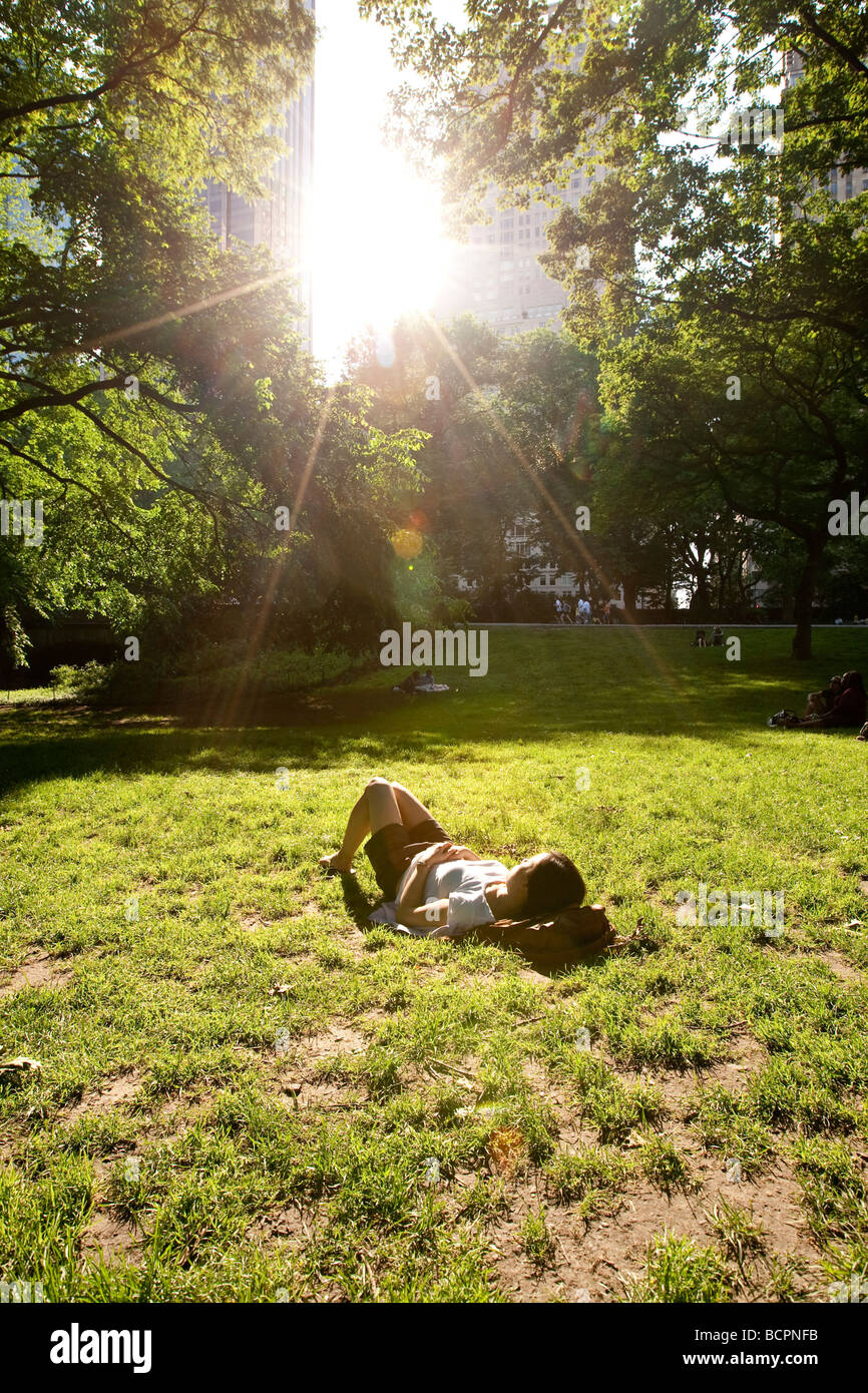 woman sleeping alone in the sun in Central Park on a warm summer day in ...