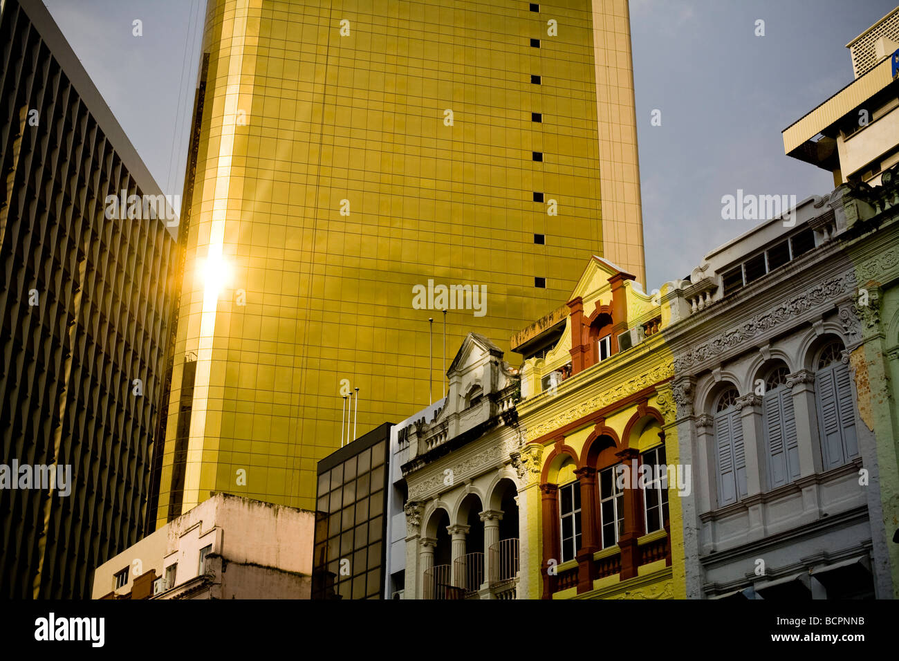 A large golden skyscraper towers above older colonial buildings in ...