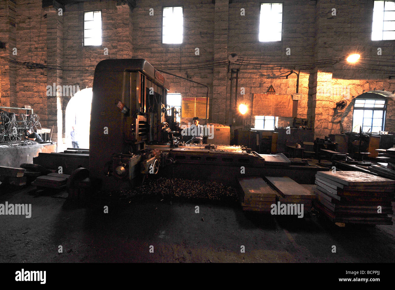 Technicians working next to lathe in old stone factory space built in ...