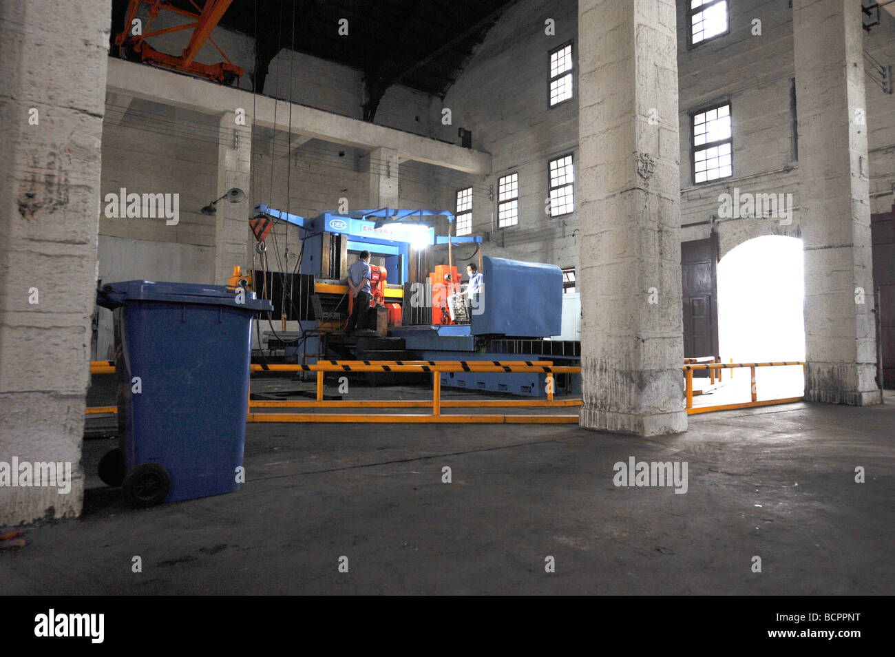 Technicians working next to lathe in old stone factory space built in ...