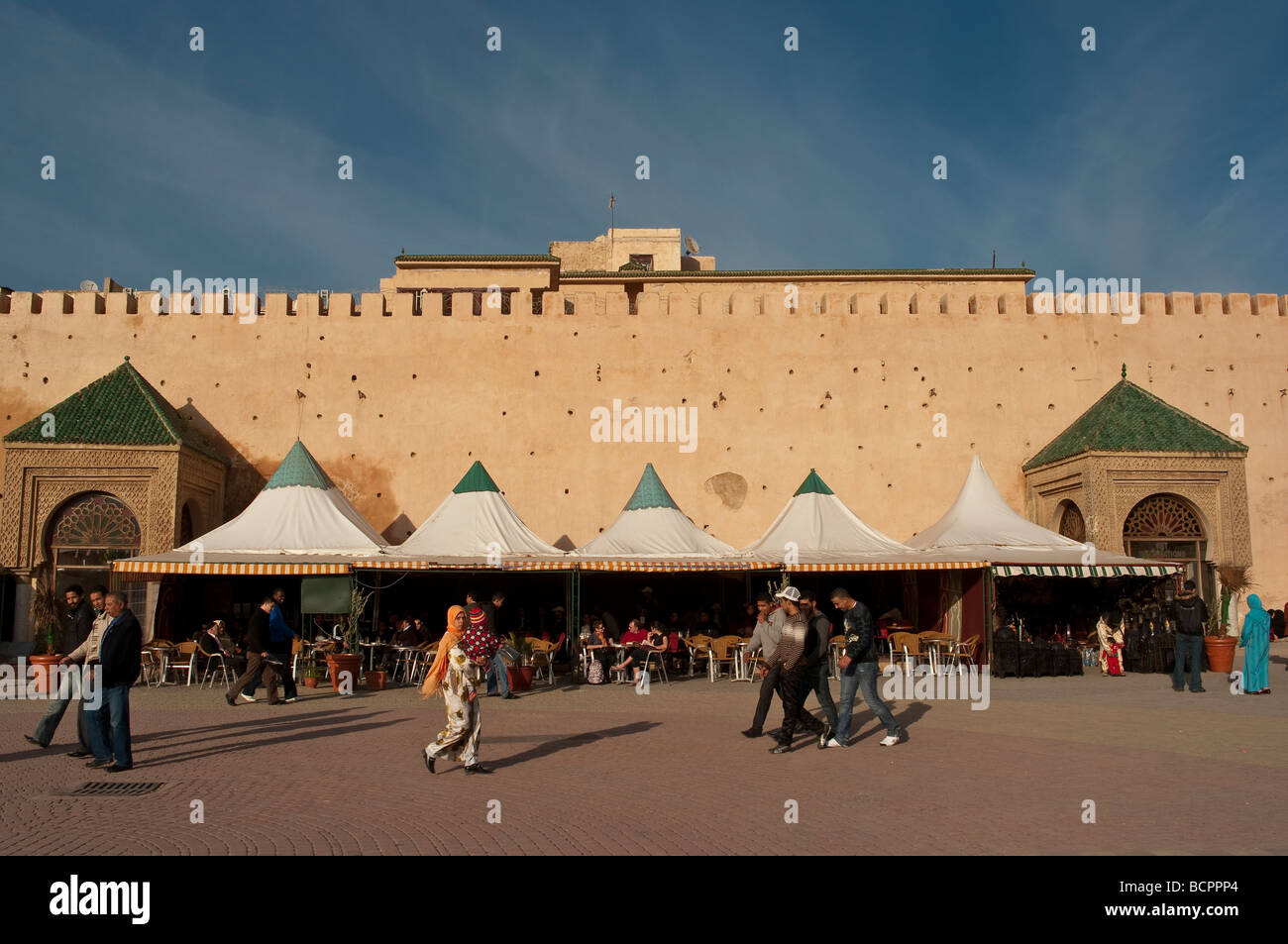 Moroccan locals passing by the ancient walls of the Medina in Meknes ...