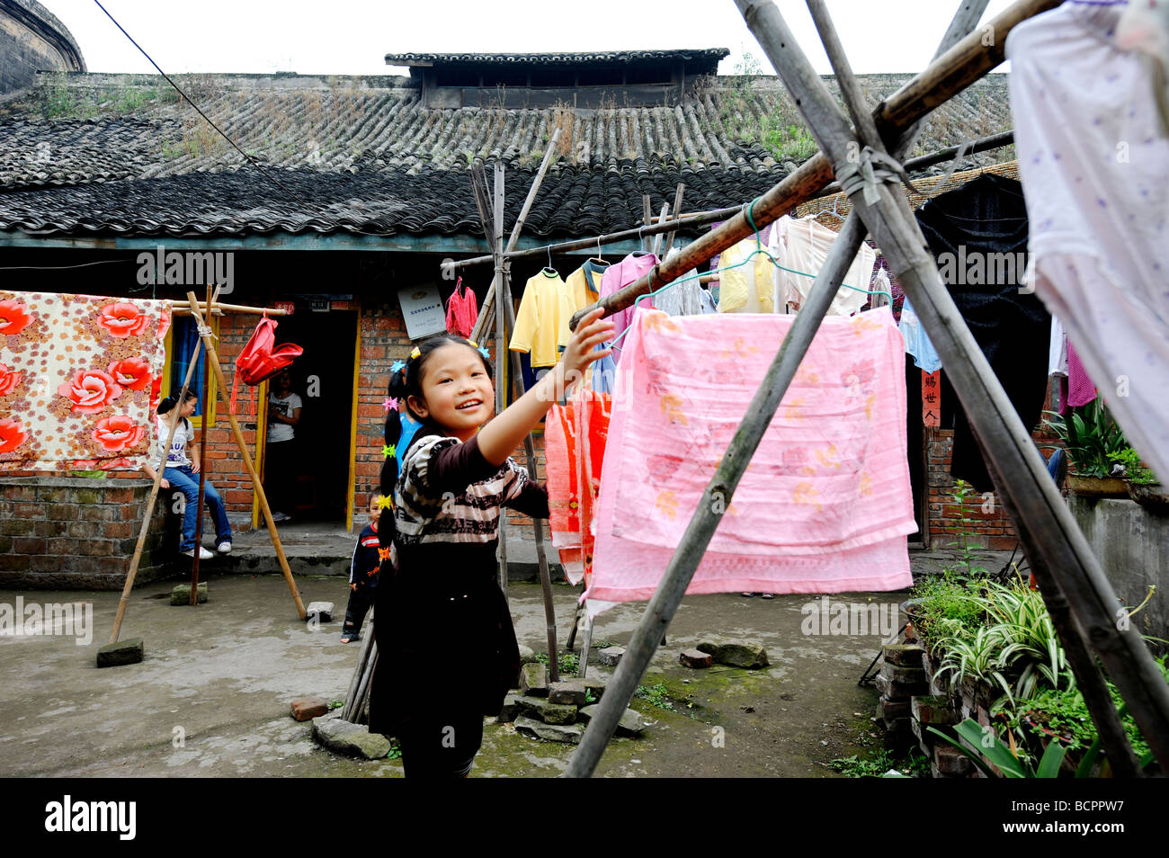 Smiling Chinese girl putting out laundry in the yard, Lizhuang Ancient ...