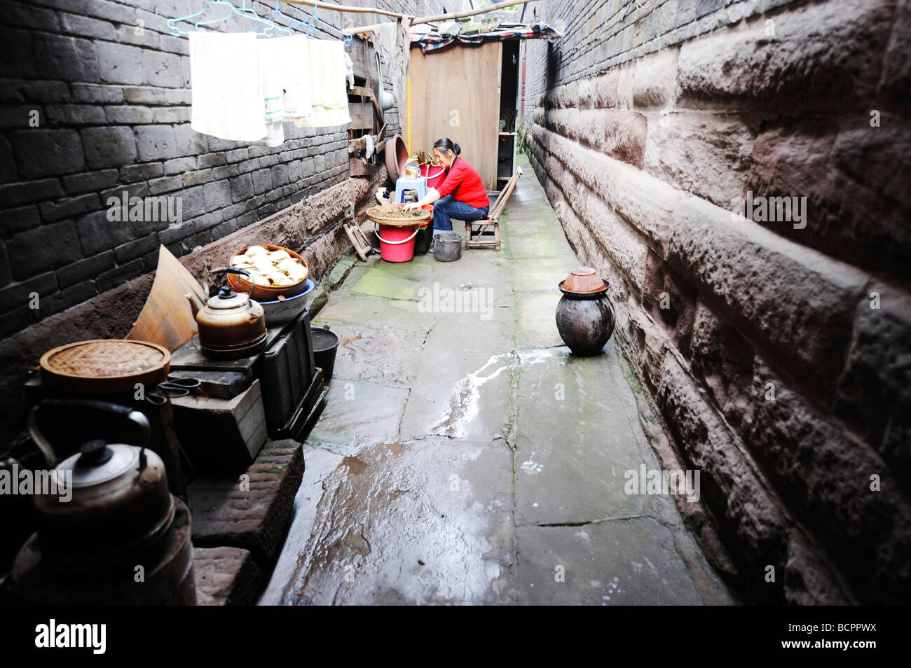 Chinese woman preparing food in a outdoor kitchen setup in the narrow ...