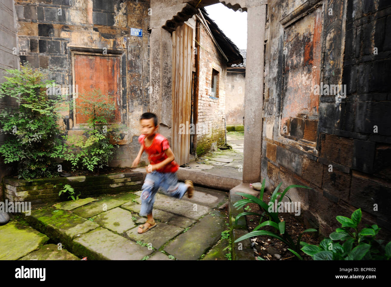 A Chinese boy running out from an old house build in Qing Dynasty ...