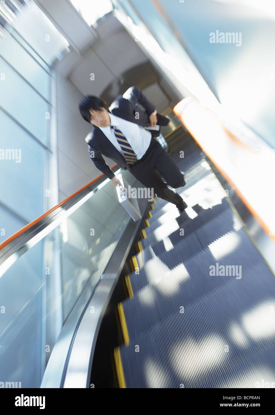Businessman running up escalator Stock Photo - Alamy