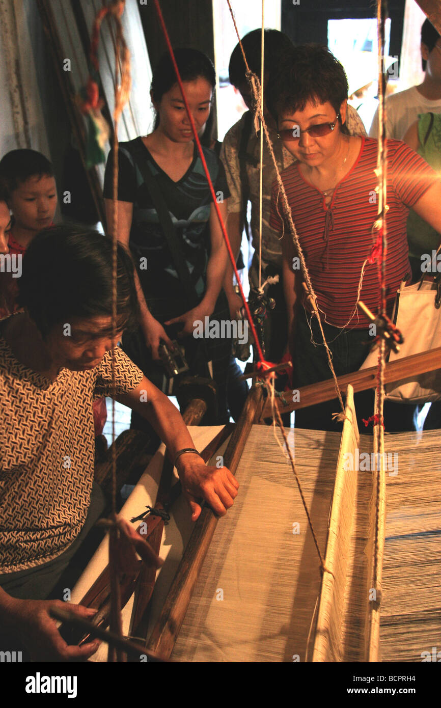 Tourists observing local craftsman weaving clothing using ancient ...