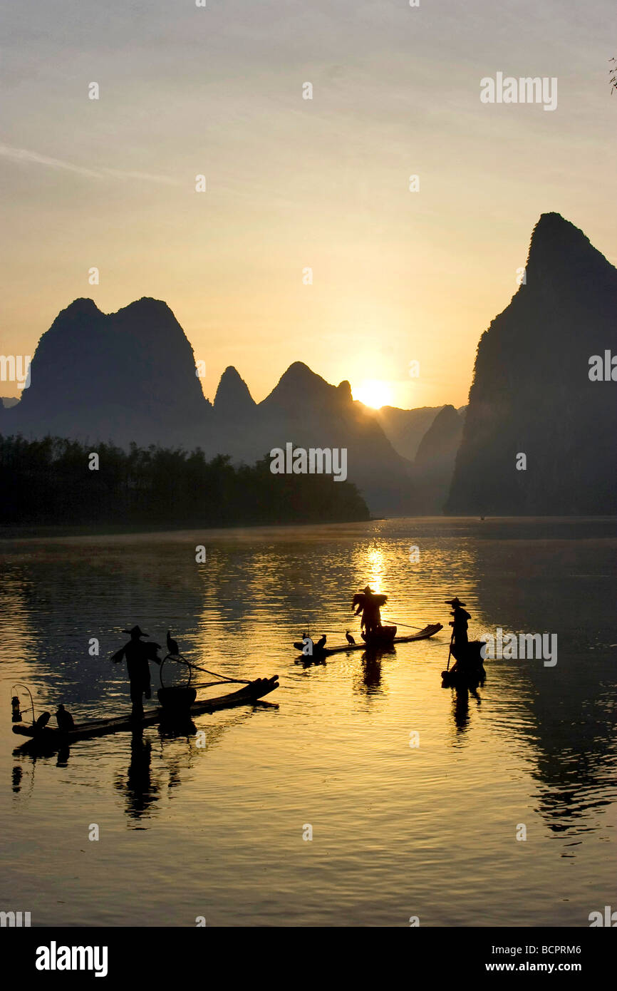 Chinese fishermen on bamboo raft fishing with cormorants at sunset on ...