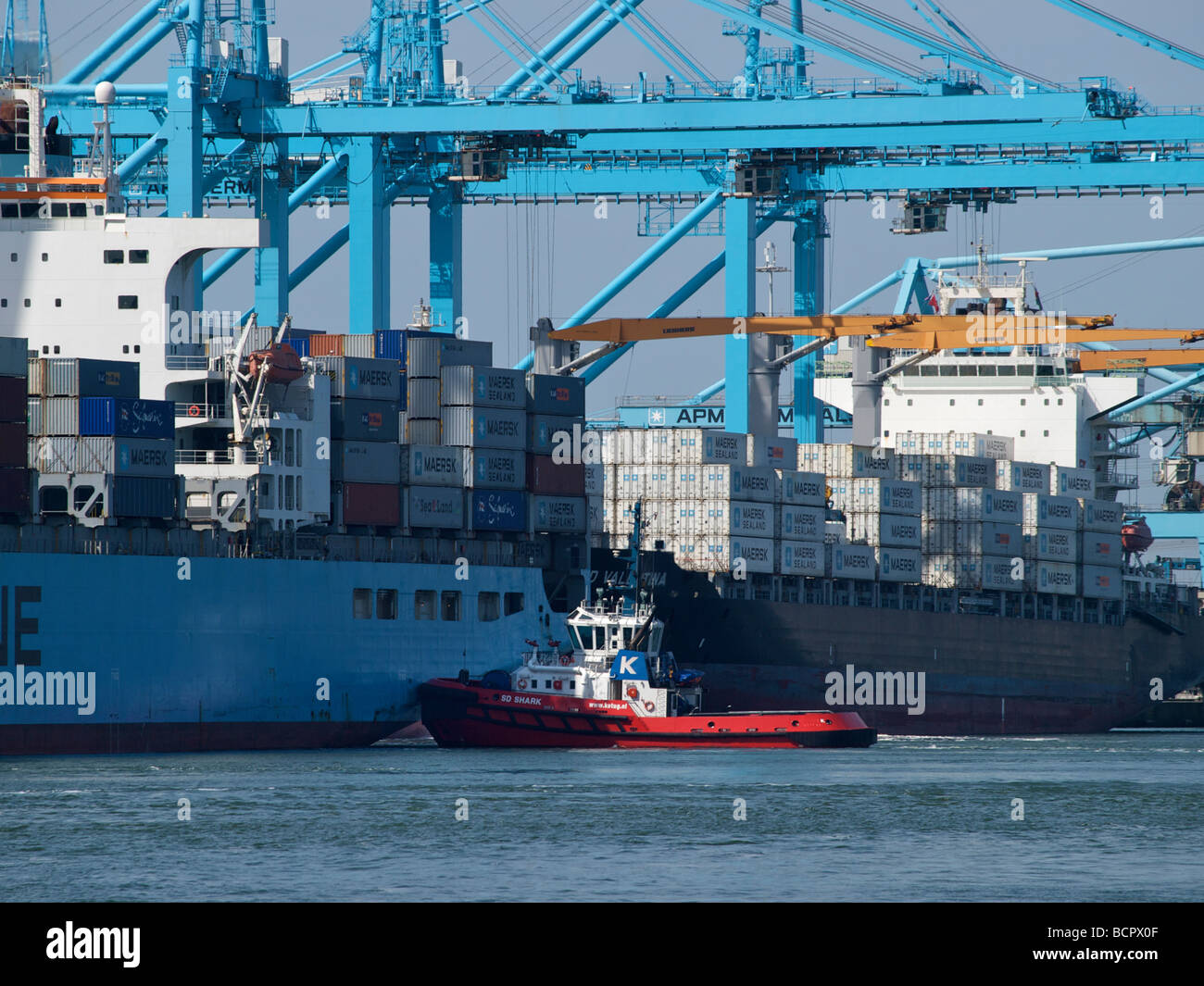 Tug boat nudging a very large container ship into place in the port of ... Tug boat nudging a very large container ship into place in the port of ...