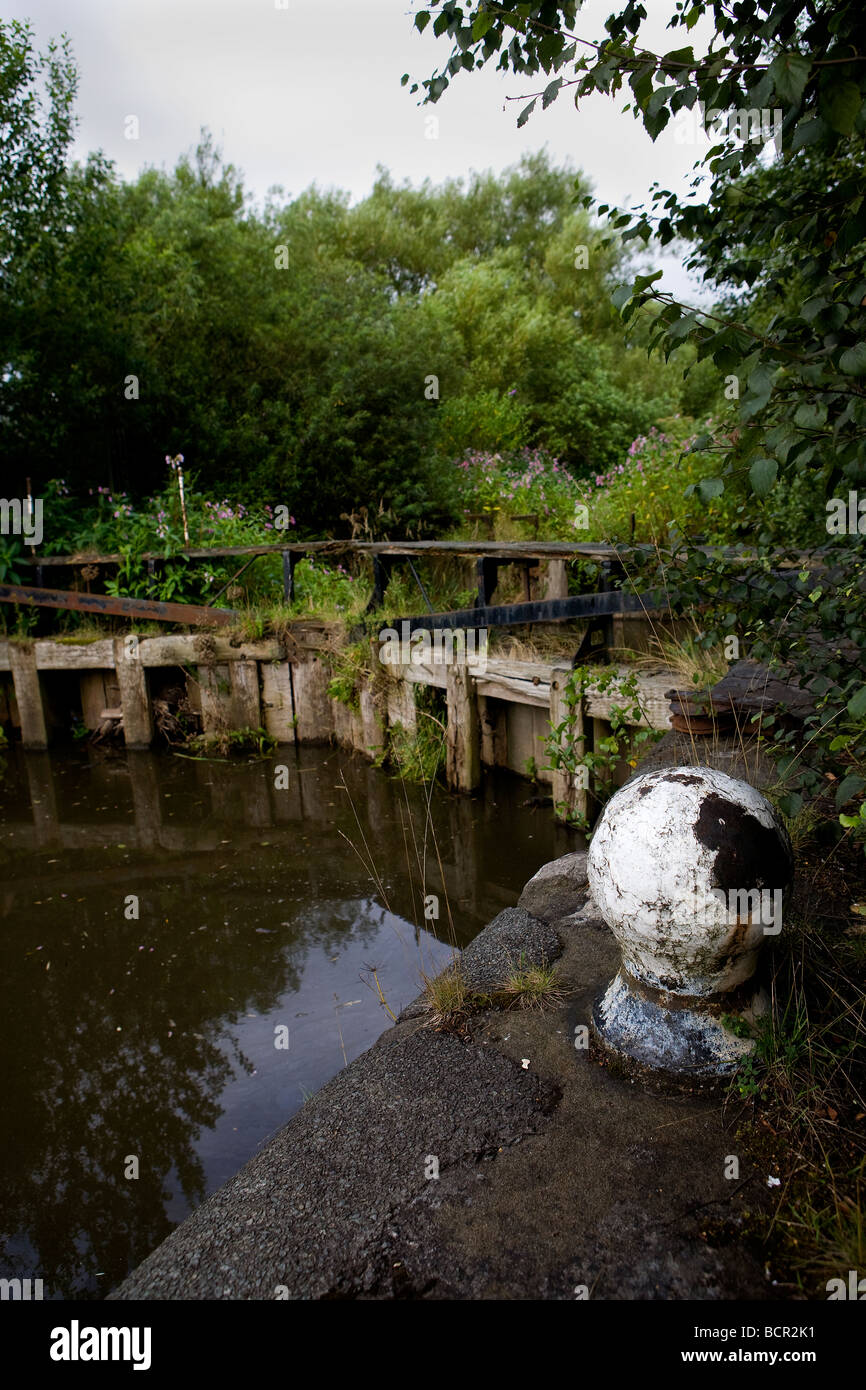 Lock gates, unused and deteriorating amongst the trees and weeds, along ...