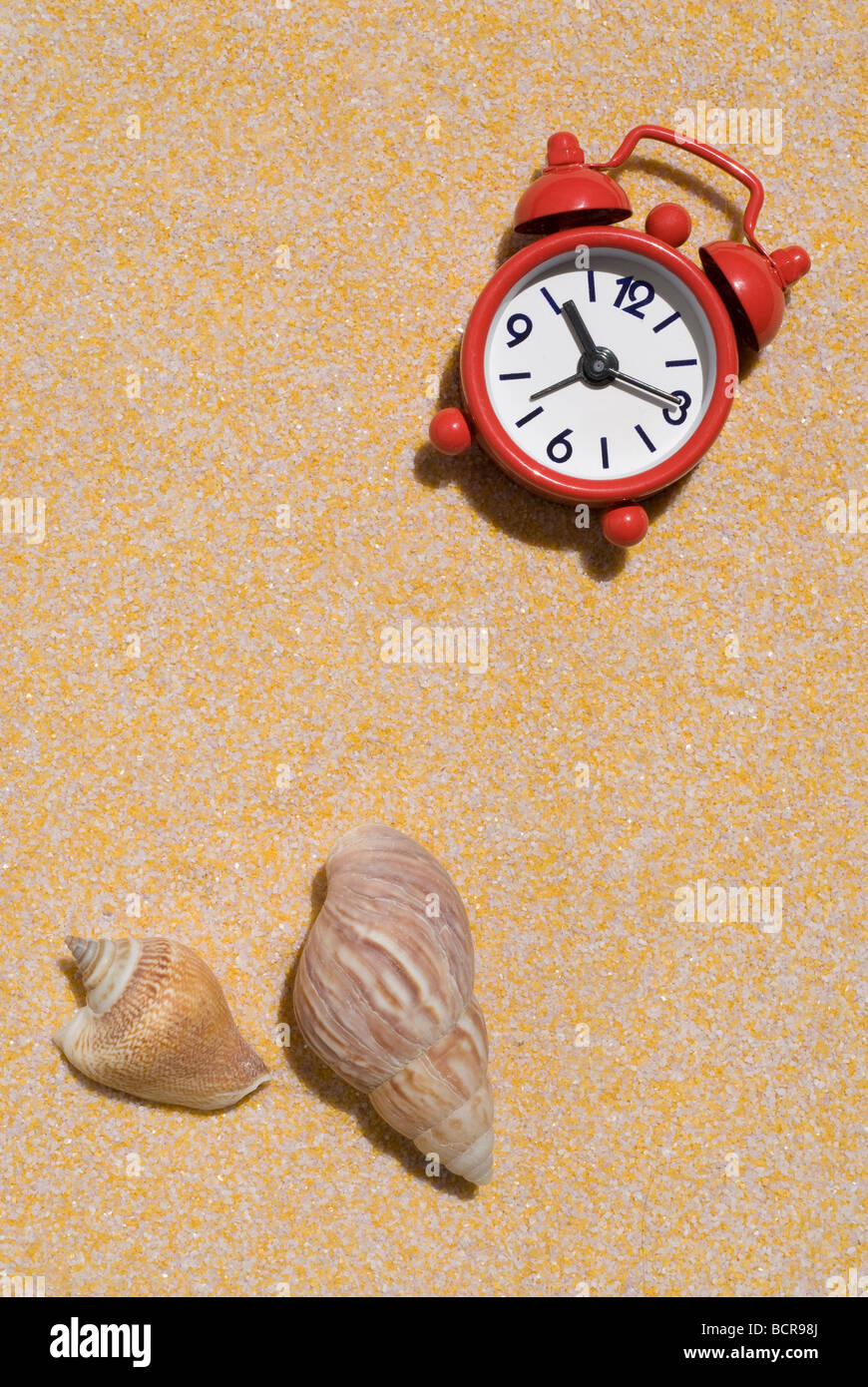 small red alarm clock on the sands with seashells Stock Photo - Alamy
