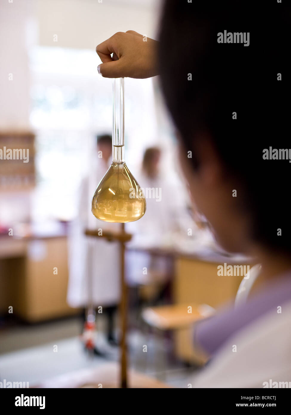 A student holding a flask of liquid in a science laboratory in a school ...