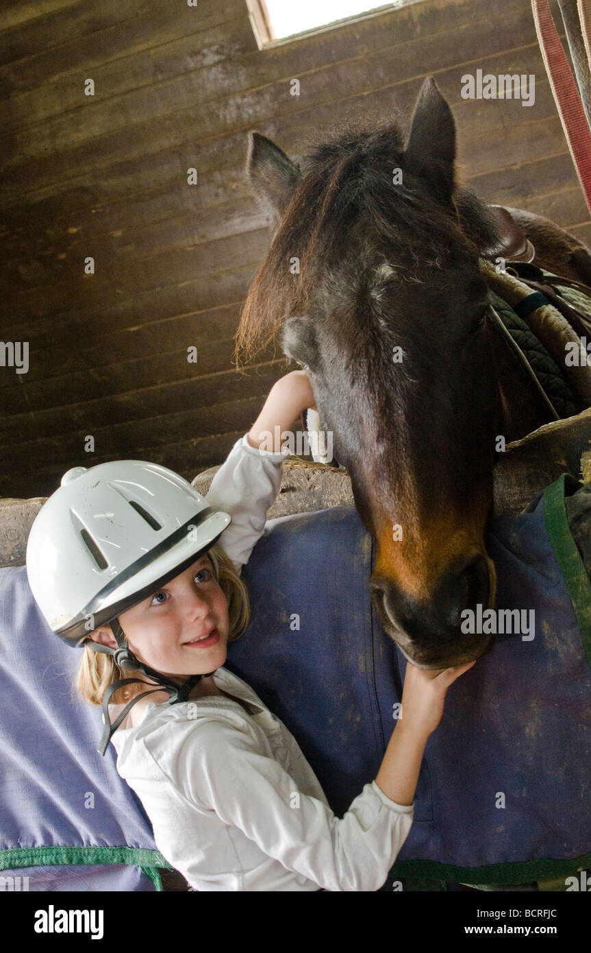 Young girl females with favorite horse in stable during horseback ...