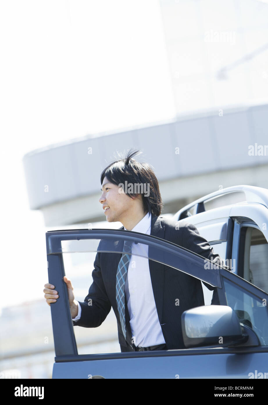Businessman getting out of a car Stock Photo - Alamy