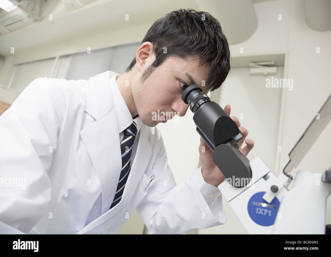 A researcher looking into microscope Stock Photo - Alamy