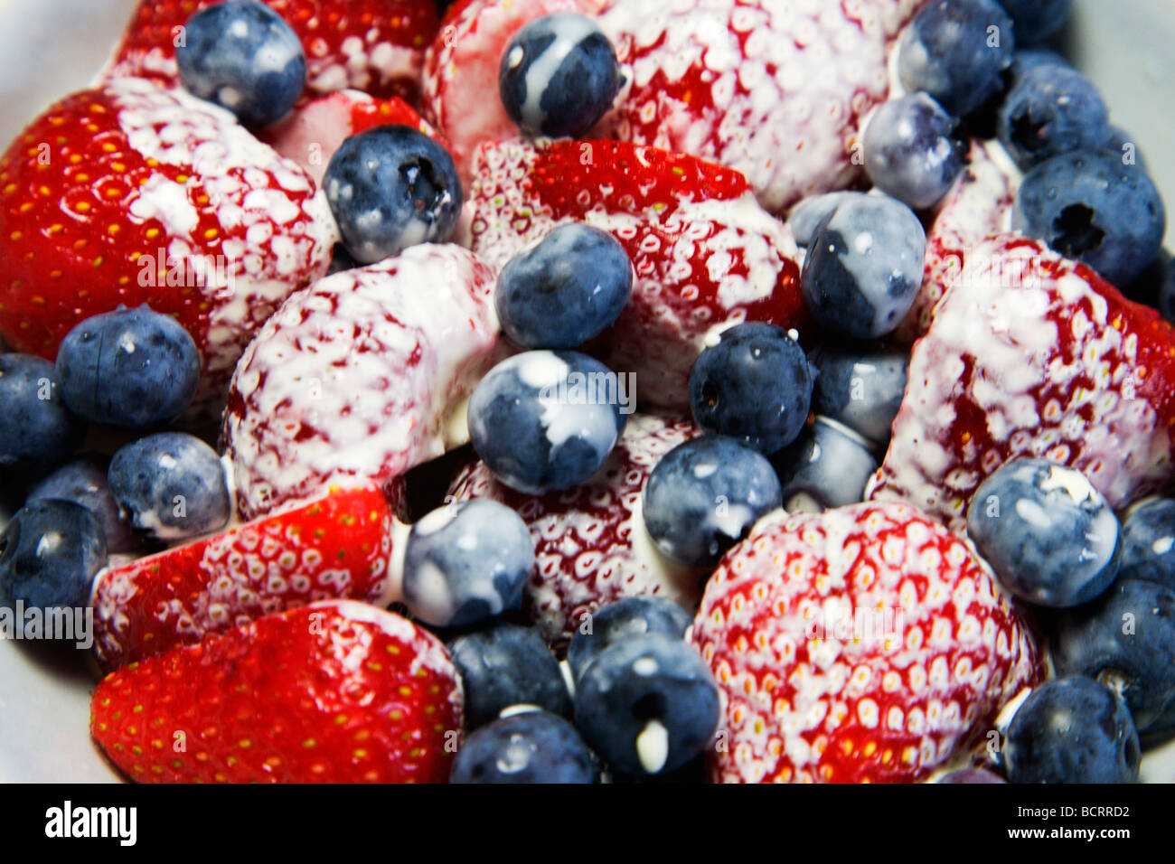 Halved strawberries with blueberries and fresh double cream Stock Photo ...