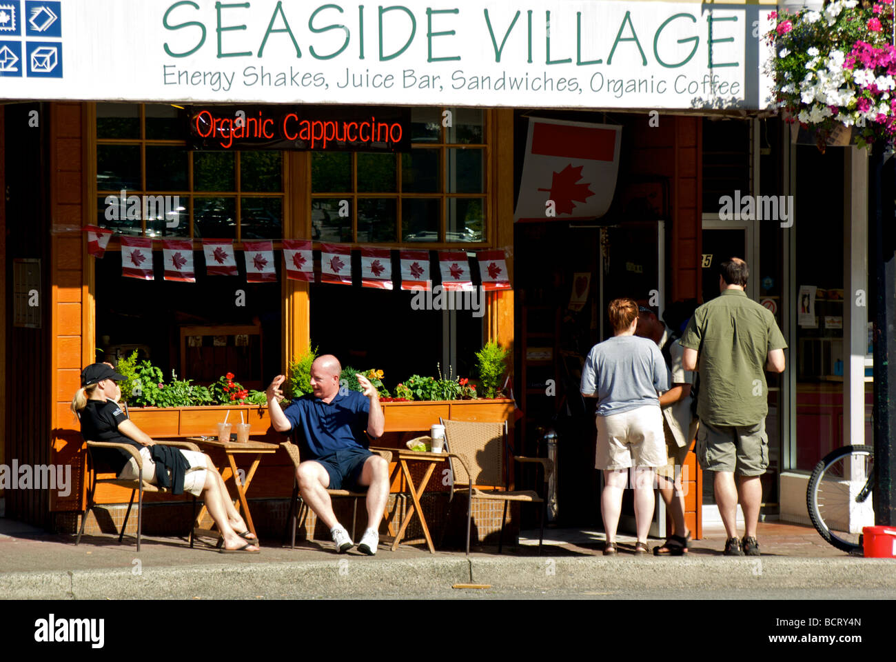 Coffee shop patrons enjoying a drink and conversation al fresco sitting ...