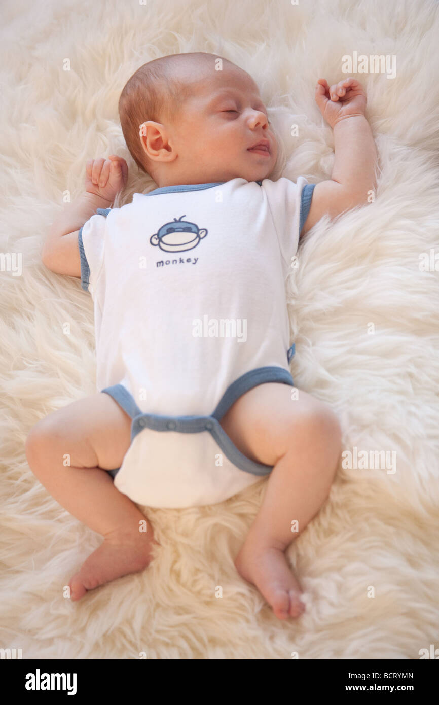Newborn baby boy sleeping on a sheepskin rug hi-res stock photography ...