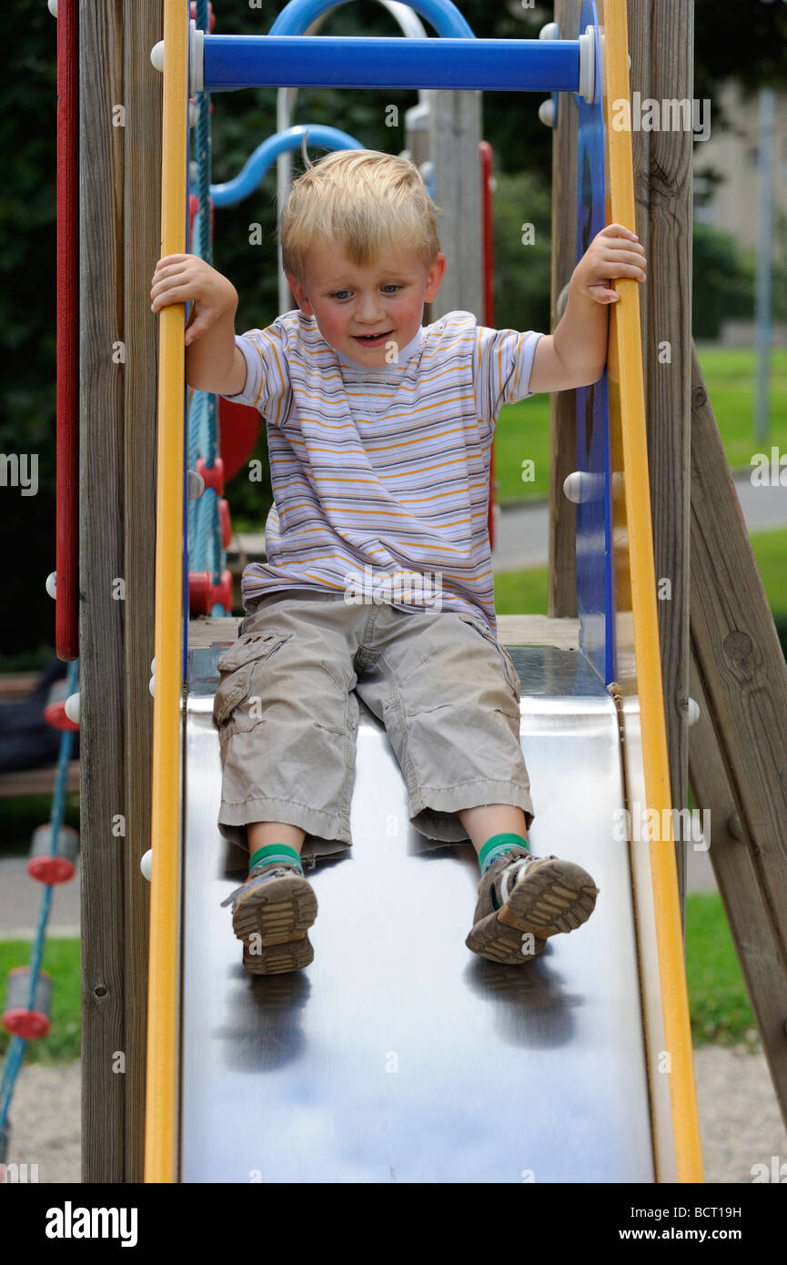 Child blonde boy sliding down the slide on the playground Stock Photo ...