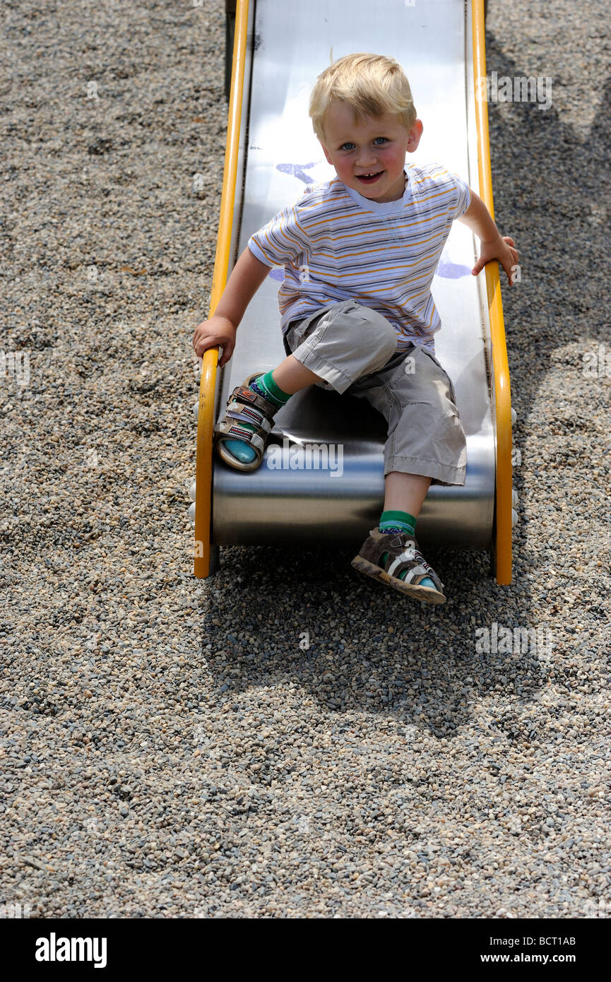 Child blonde boy sliding down the slide on the playground Stock Photo ...