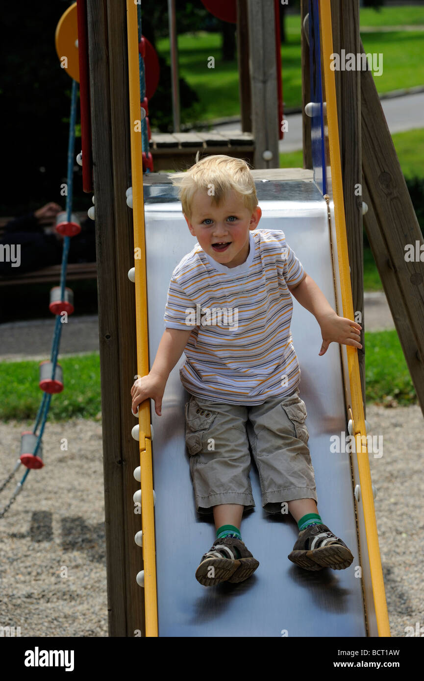 Child blonde boy sliding down the slide on the playground Stock Photo ...