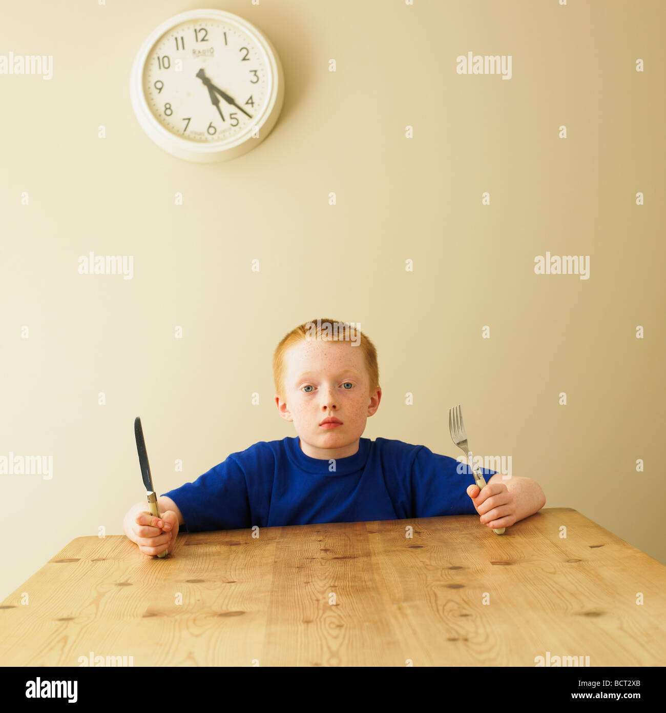 Young boy waiting for his dinner with a clock on the wall above Stock ...