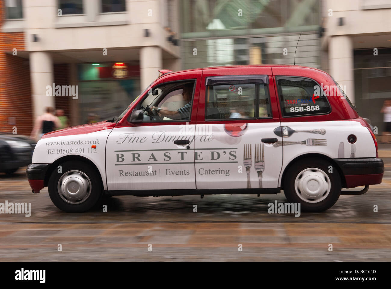 A taxi driving through the city centre in the rain showing movement in ...