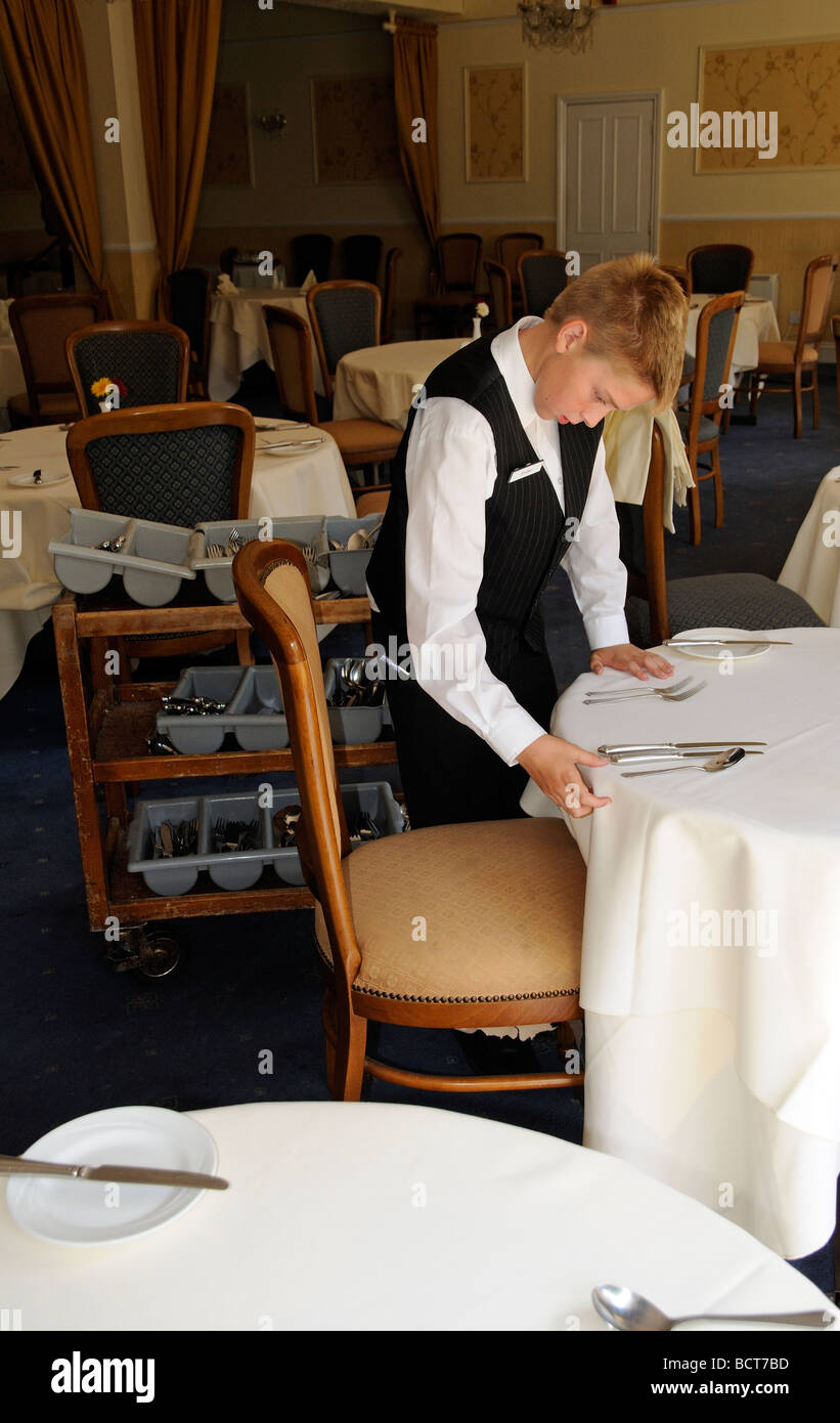 Work experience student laying up a table for lunch service in a hotel ...