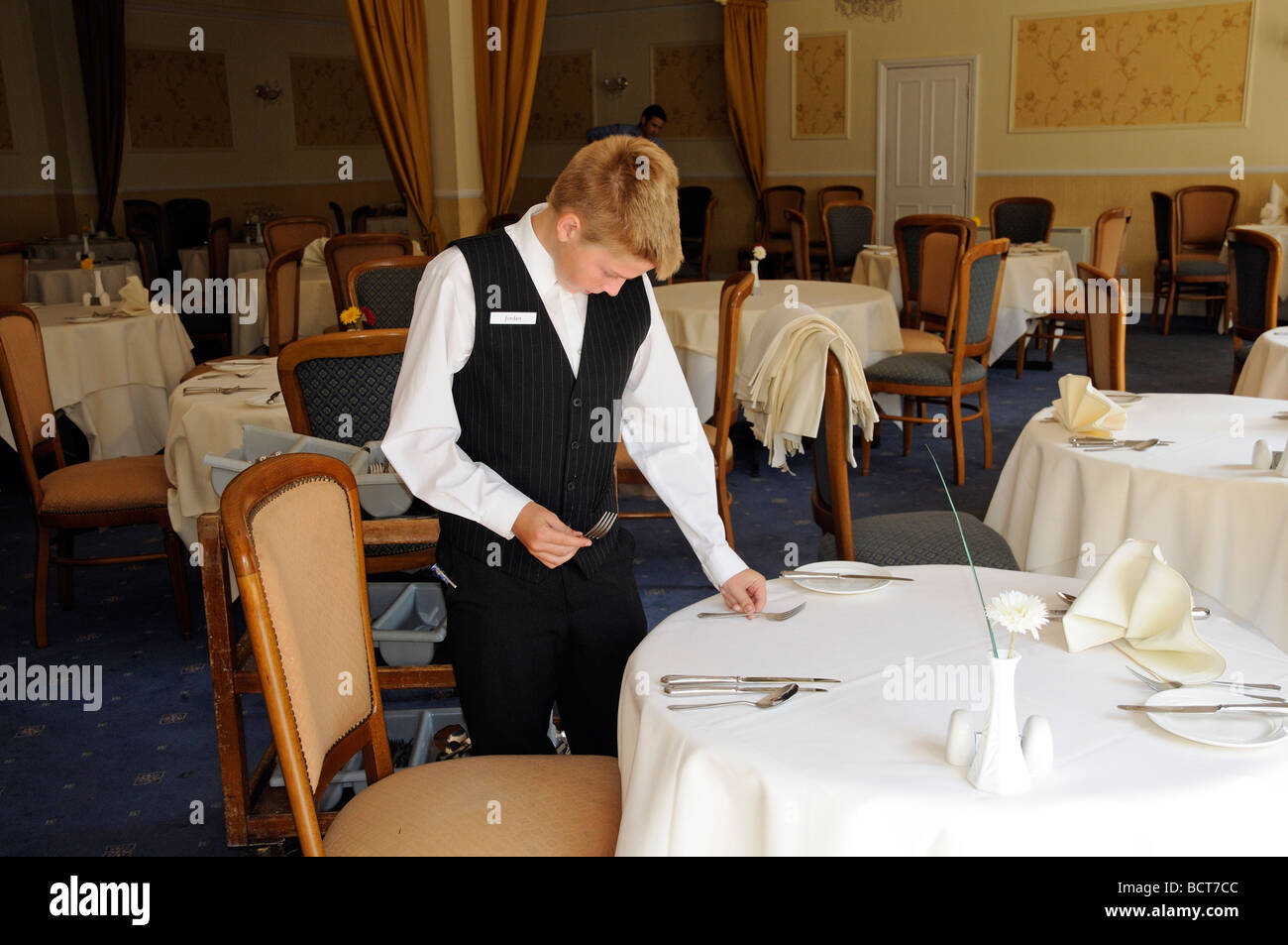 Work experience student laying up a table for lunch service in a hotel ...