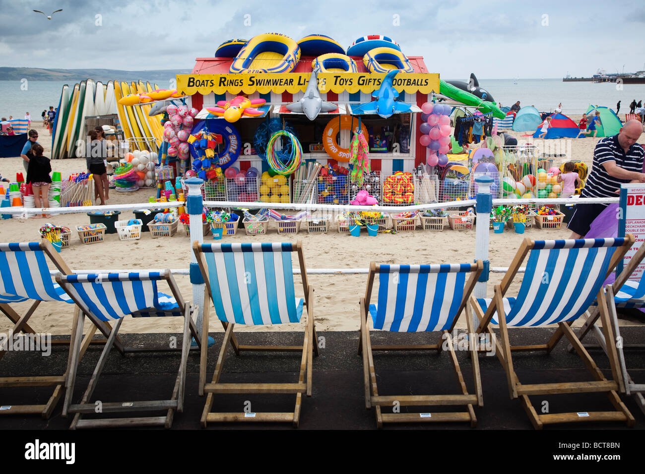 A row of empty deack chairs infront of a beach traders stall selling ...