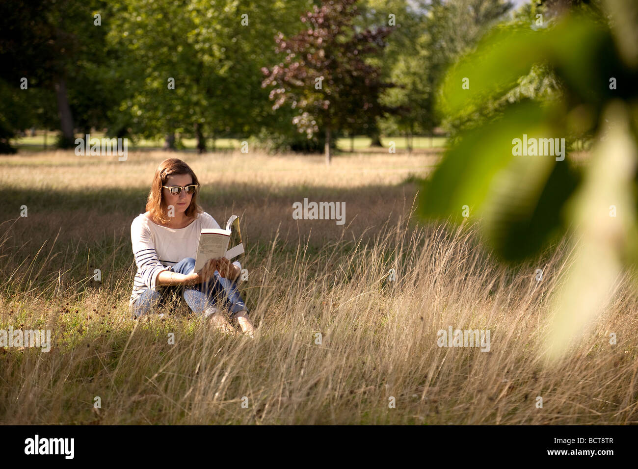 Girl reading outside in the park Stock Photo - Alamy