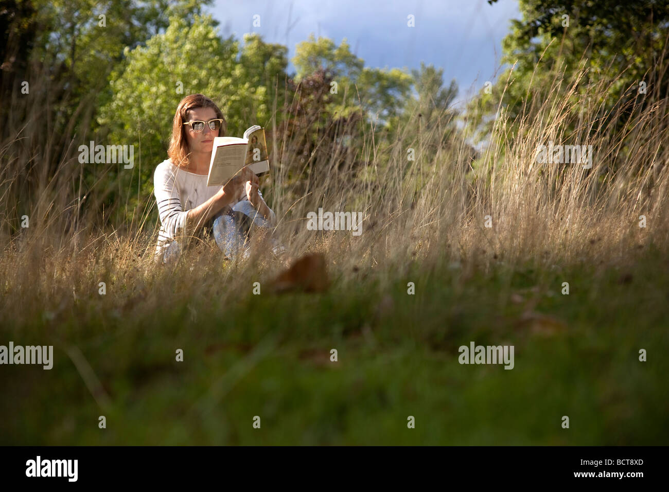 Girl reading outside in the park Stock Photo - Alamy