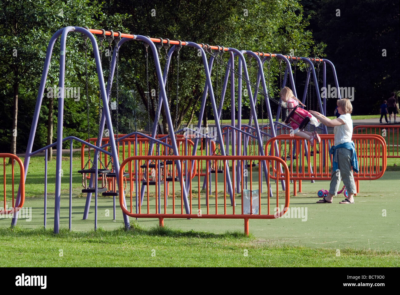 Woman pushing a small girl on a swing in a park playground Stock Photo ...