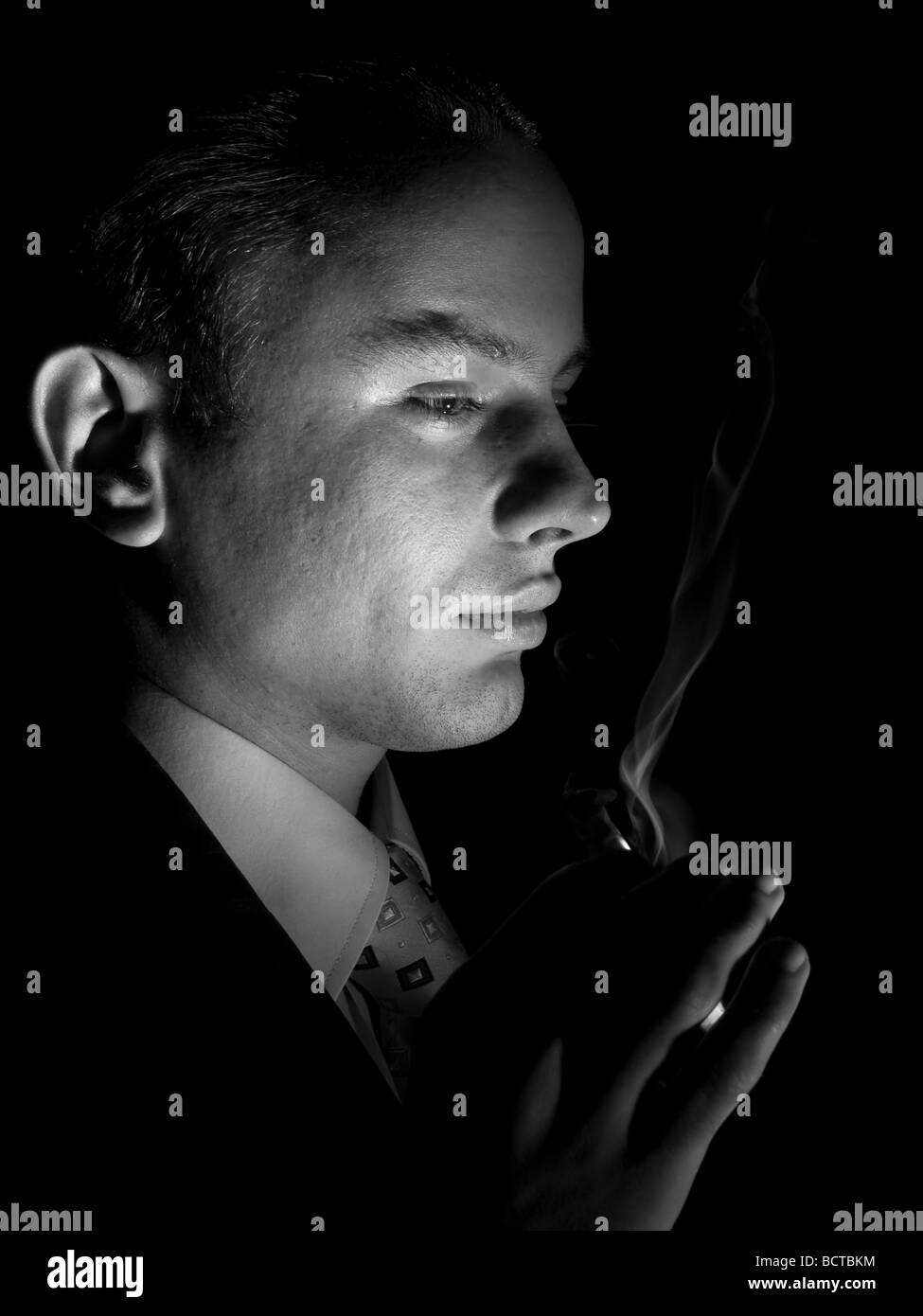Young man in suit smoking cigarette side view Stock Photo - Alamy