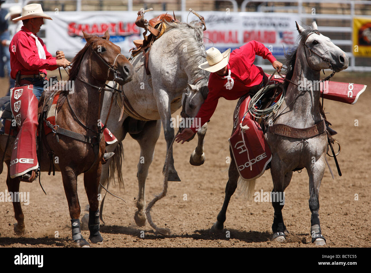 A pickup rider grabs the rein of a bronc during the saddle bronc ...