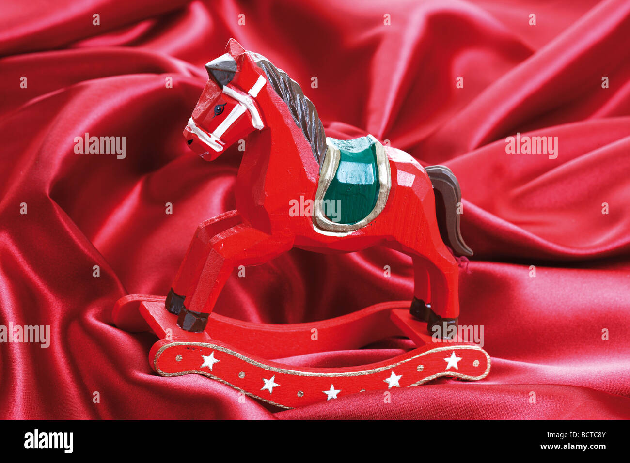 Miniature rocking horse on red fabric Stock Photo - Alamy