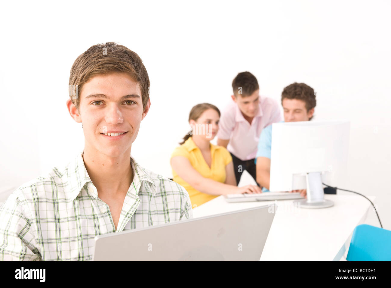 Portrait of a boy, three adolescents working on a computer in the back ...