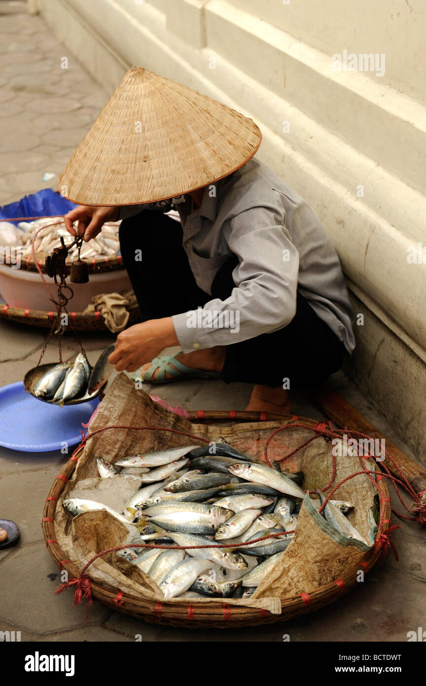 Street hawker measuring river fish with traditional scale in old ...