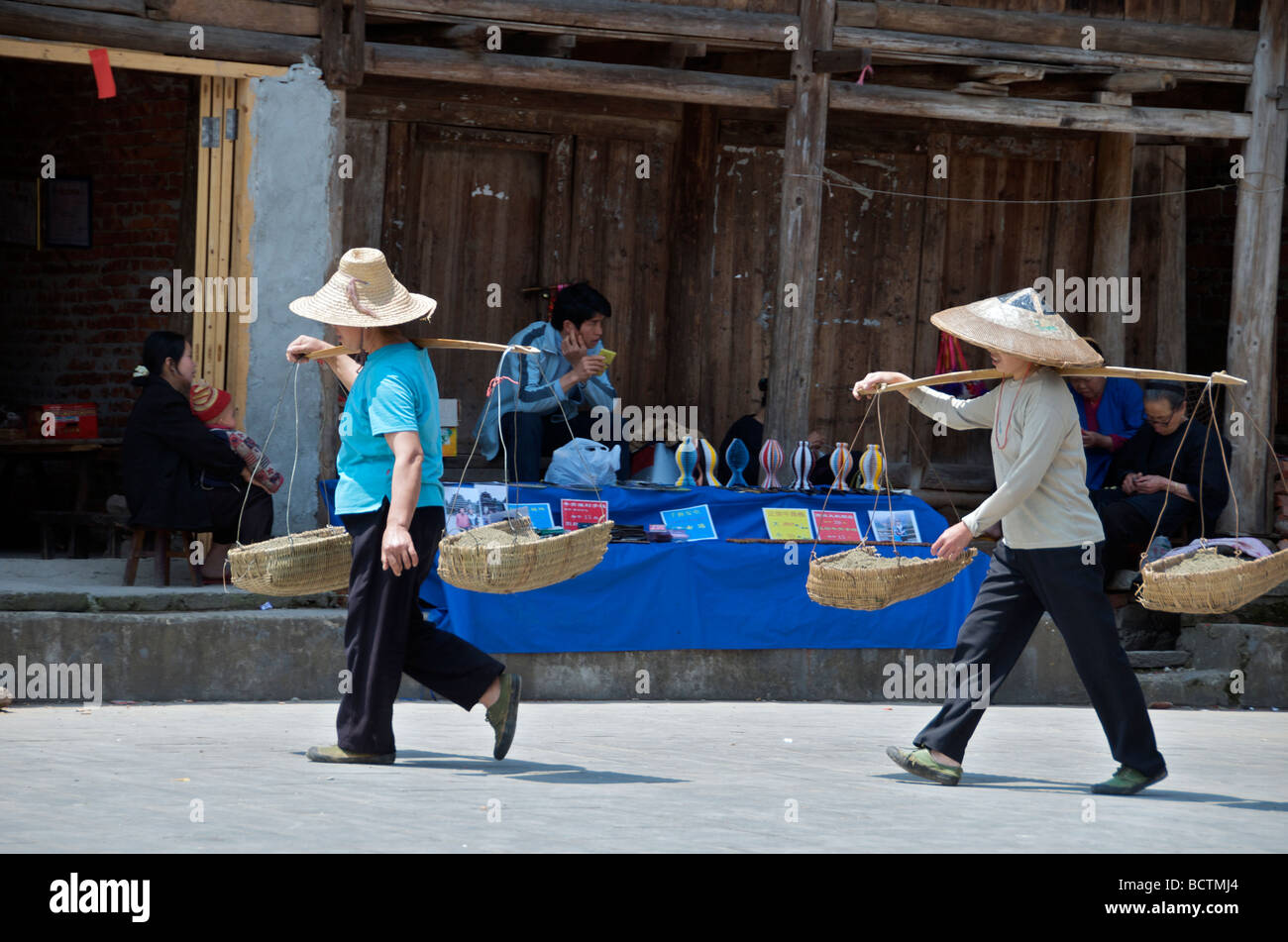 Two women carrying sand in a traditional method with basket and pole ...