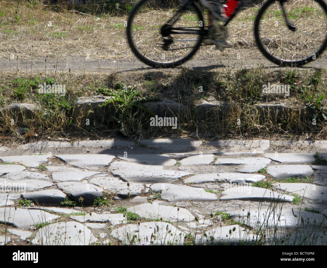 person riding bike on the ancient roman old appian way, rome, italy ...