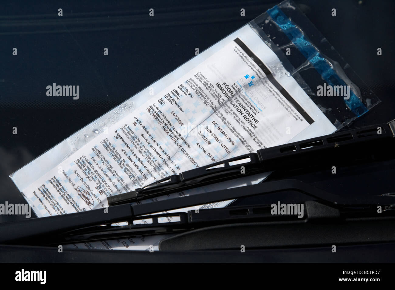 immobilisation notice on windscreen of car clamped with wheelclamp in ...