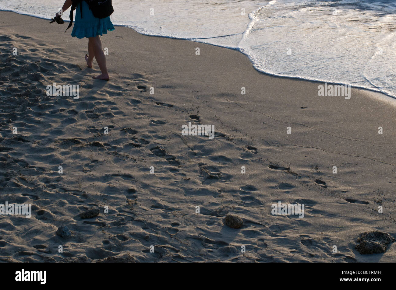 A woman walking across the beach at Sennen Stock Photo - Alamy