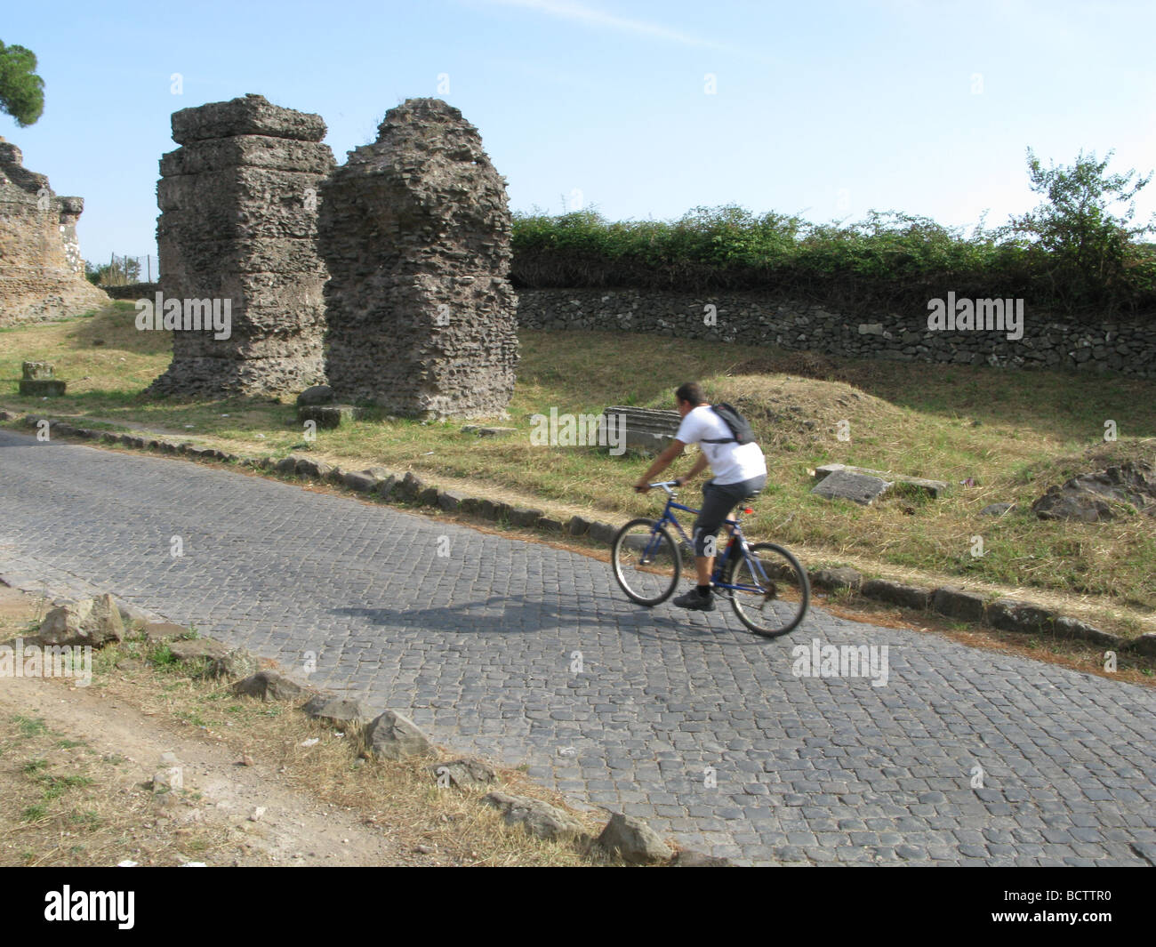 person riding bike on the ancient roman old appian way, rome, italy ...