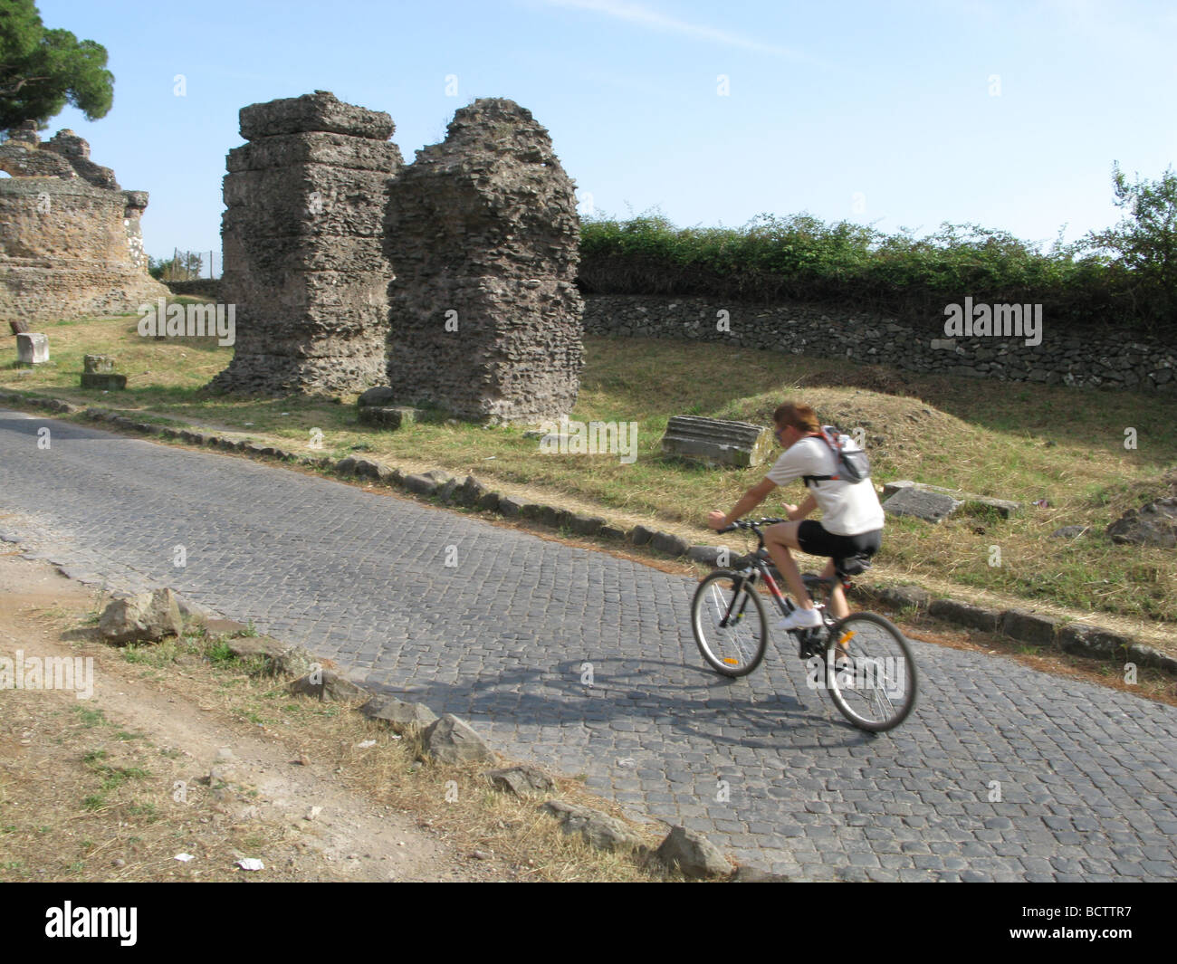 person riding bike on the ancient roman old appian way, rome, italy ...
