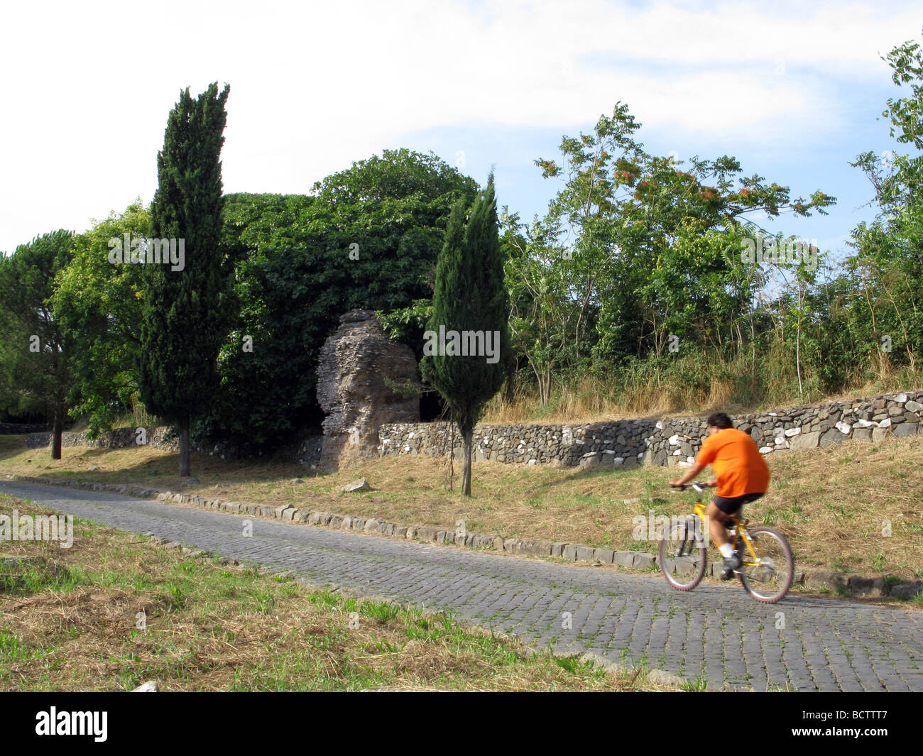 person riding bike on the ancient roman old appian way, rome, italy ...